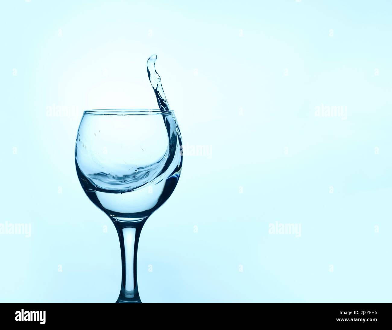 glass of clean water with a splash on a light background with copy ...