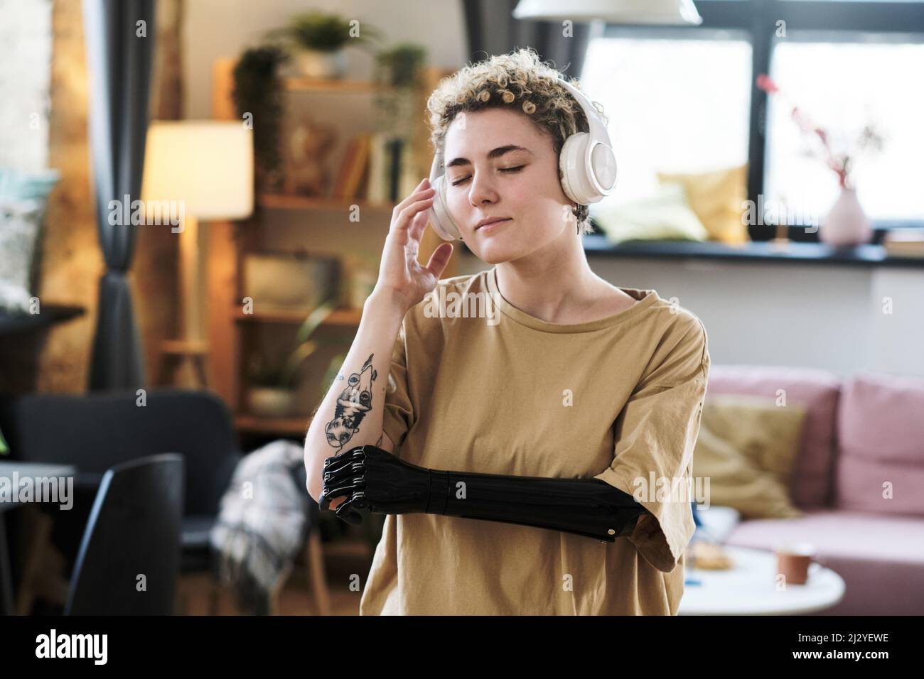 Young woman with prosthetic arm in wireless headphones enjoying the ...