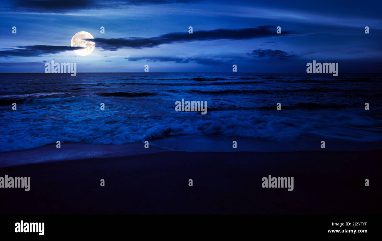calm sea scenery at night. waves wash empty sandy beach in full moon ...