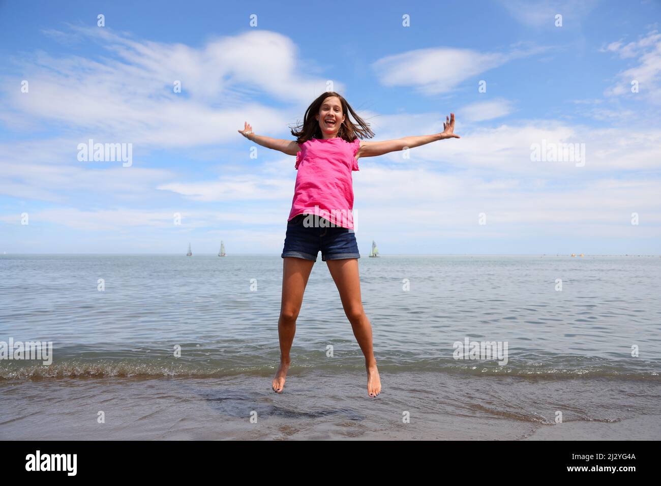 slender young girl with short pants stands a very high jump and is very ...