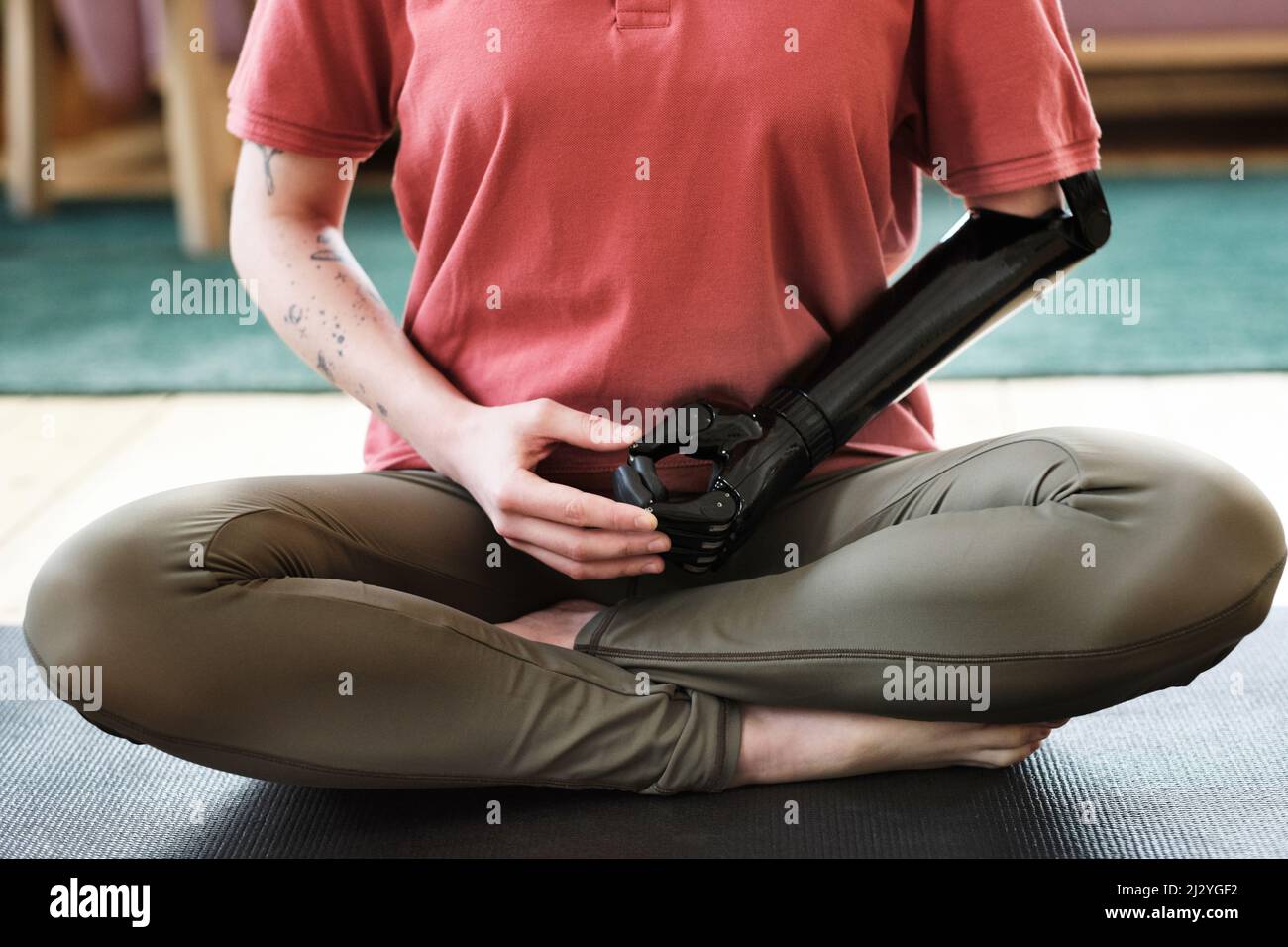 Close-up of young woman with prosthetic arm sitting in lotus position ...