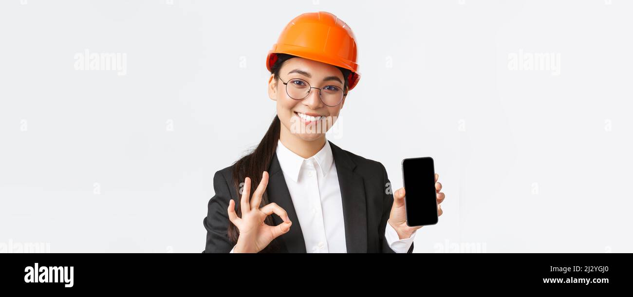 Satisfied young female asian engineer, architect in suit and safety ...
