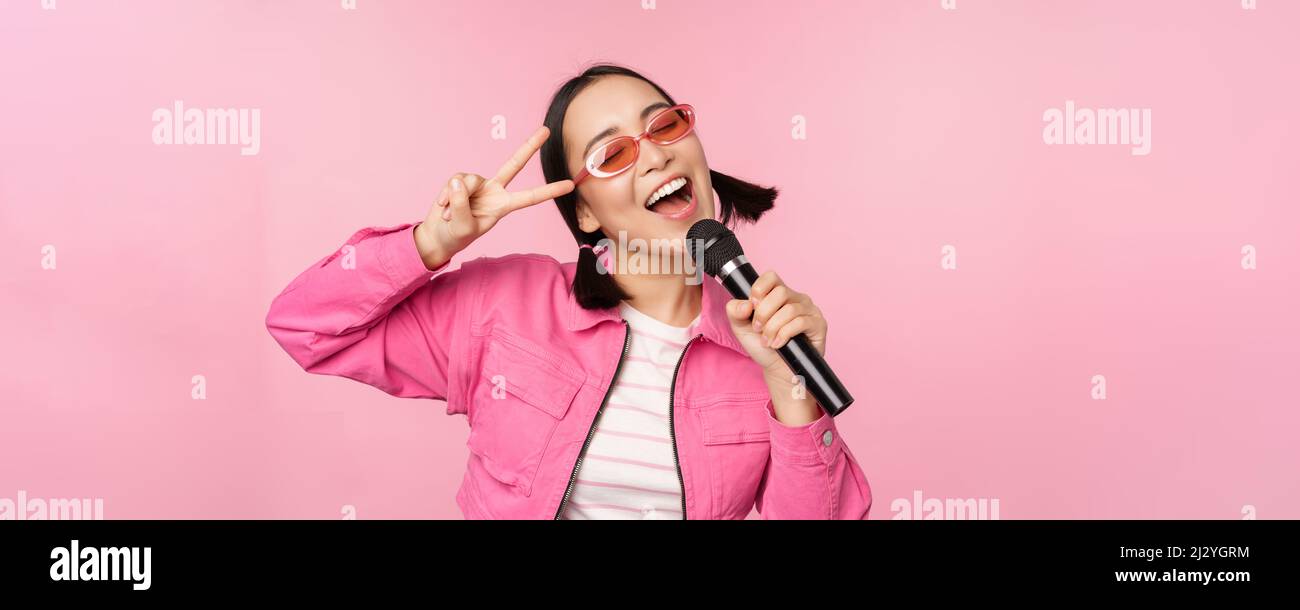 Happy beautiful asian girl singing with mic, using microphone, enjoying ...