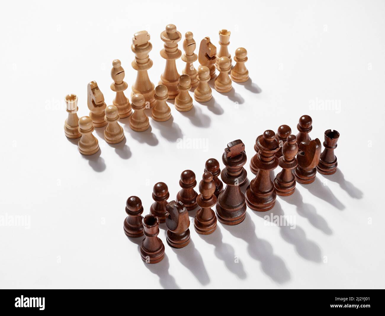 Brown and white wooden chess pieces confront on white background ...