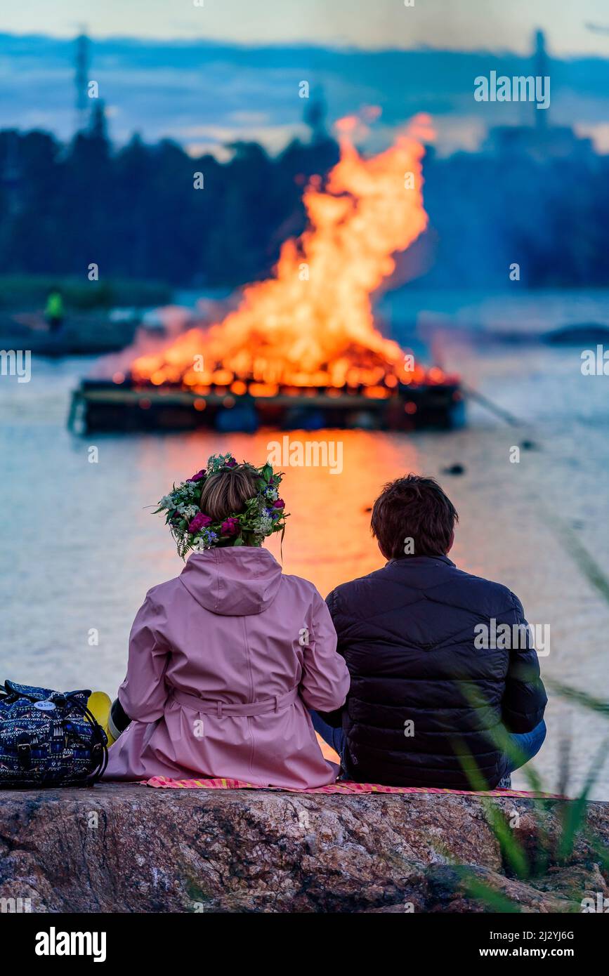 Couple looks at fire in lake, Midsummer festival in Seurasaari Open Air ...