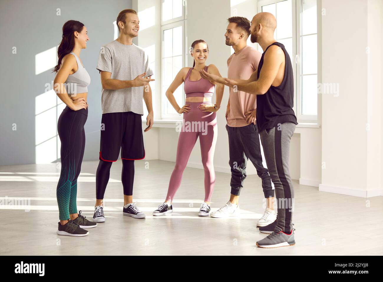 Group of happy friends talking while standing in the gym after a ...