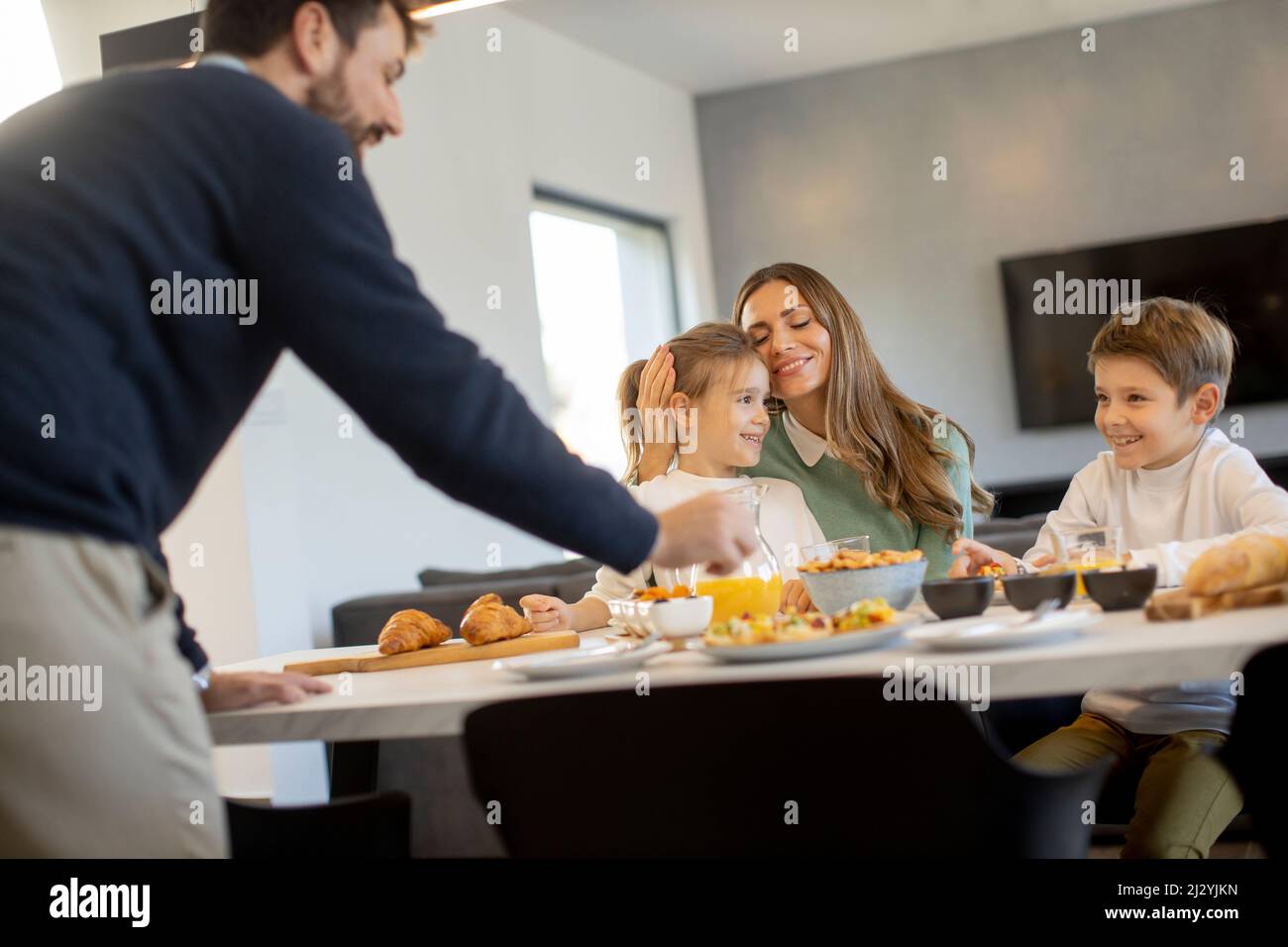 Young happy family talking while having breakfast at dining table at ...
