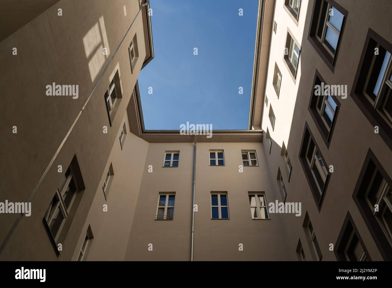 Looking up between tall buildings to the blue sky. Facades of houses in ...