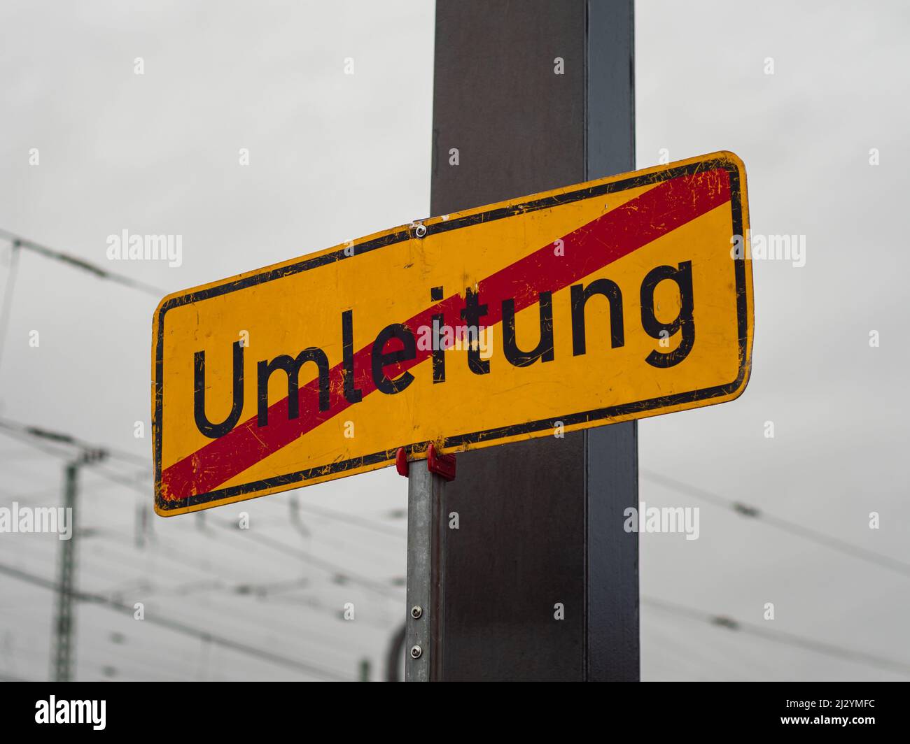 End of a redirection traffic sign next to a city street. Yellow metal ...