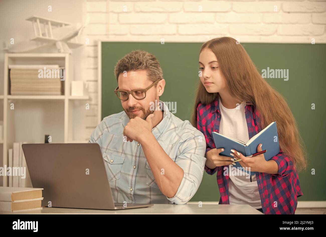 attentive kid and dad sitting in classroom with copybook and computer ...