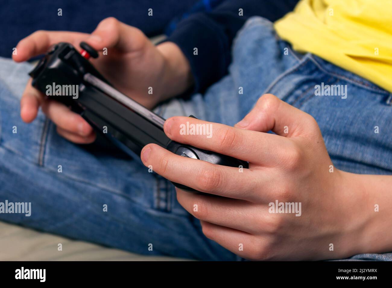 Teenager playing on his phone with console Stock Photo - Alamy