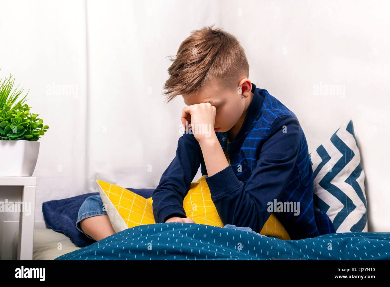 Distraught teenager sitting on bed in room Stock Photo - Alamy