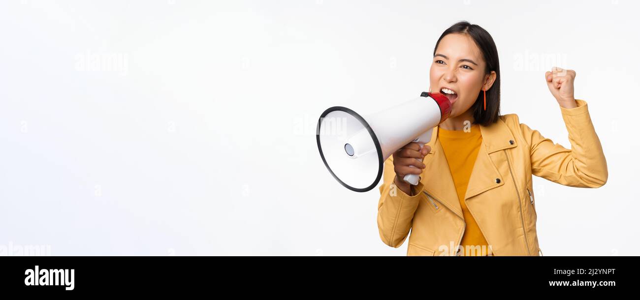Portrait of young asian woman protester, screaming in megaphone and ...