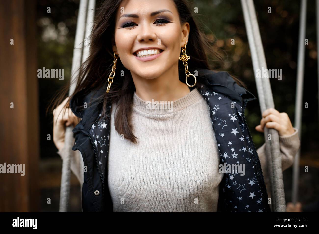 Portrait of a young happy asian woman with a snow-white smile swinging ...