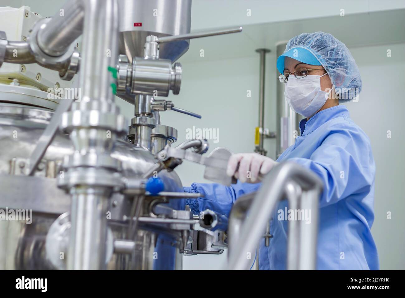 Preparing machine for work in pharmaceutical factory. Female worker ...