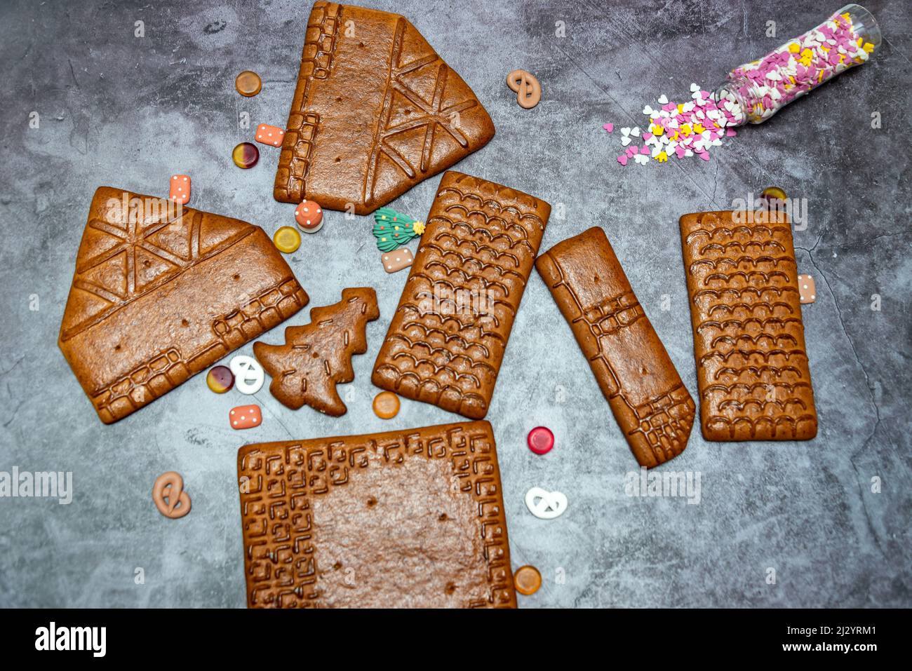 A top view of gingerbread house parts and decorations on a gray ...