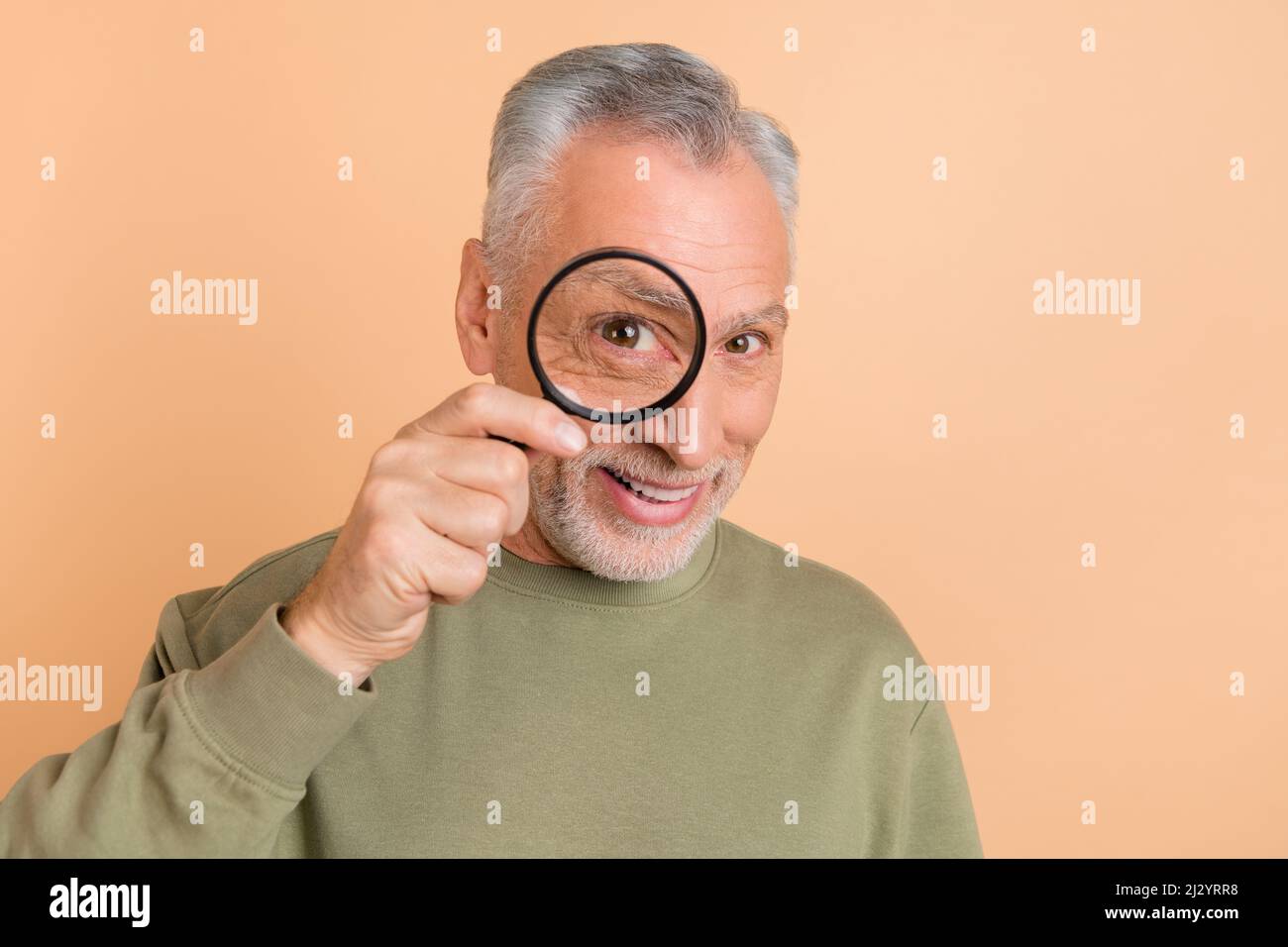 Photo of cheerful senior man watching through loupe ophthalmology check ...