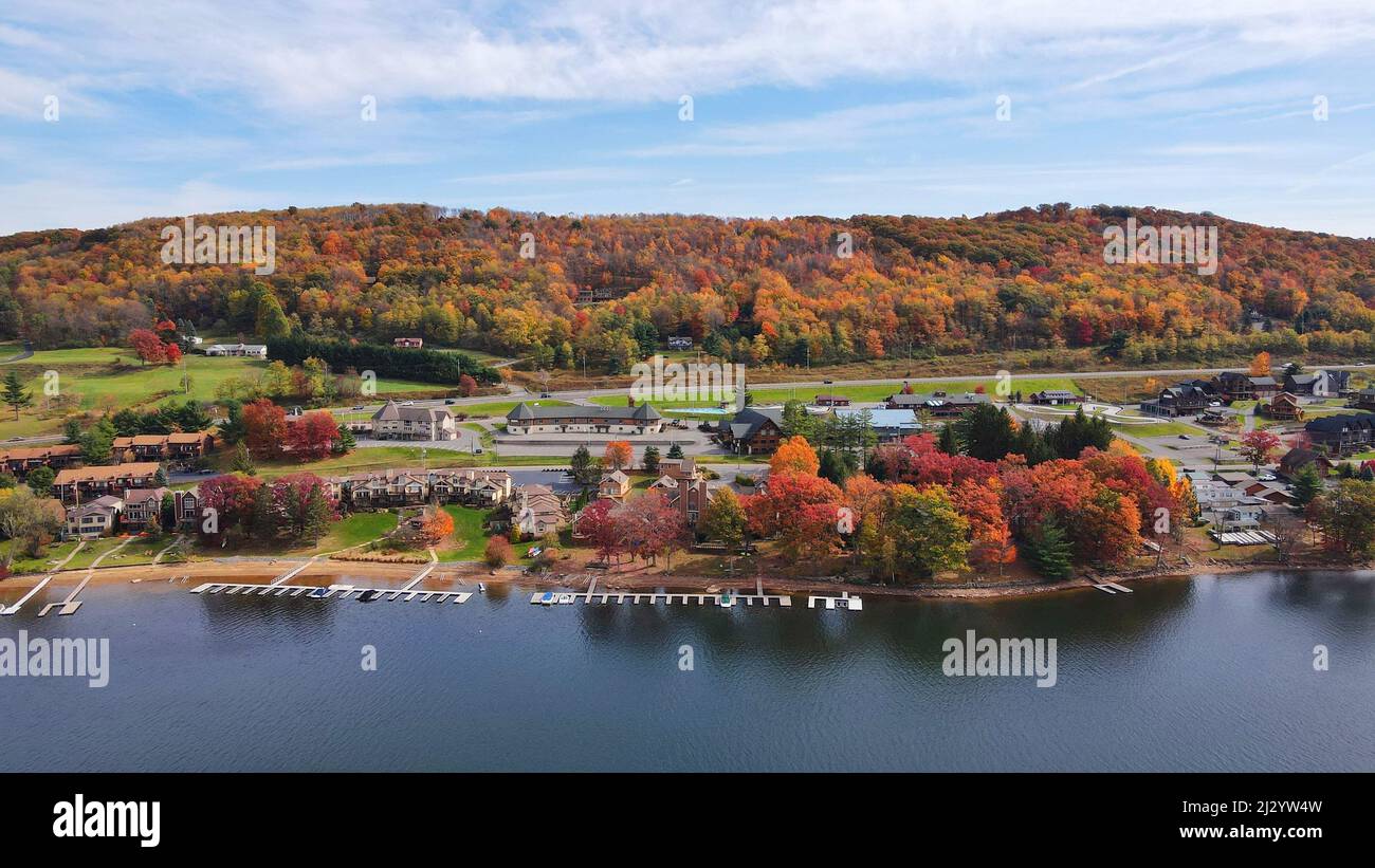 An aerial view of lakeside buildings surrounded by colorful trees and ...