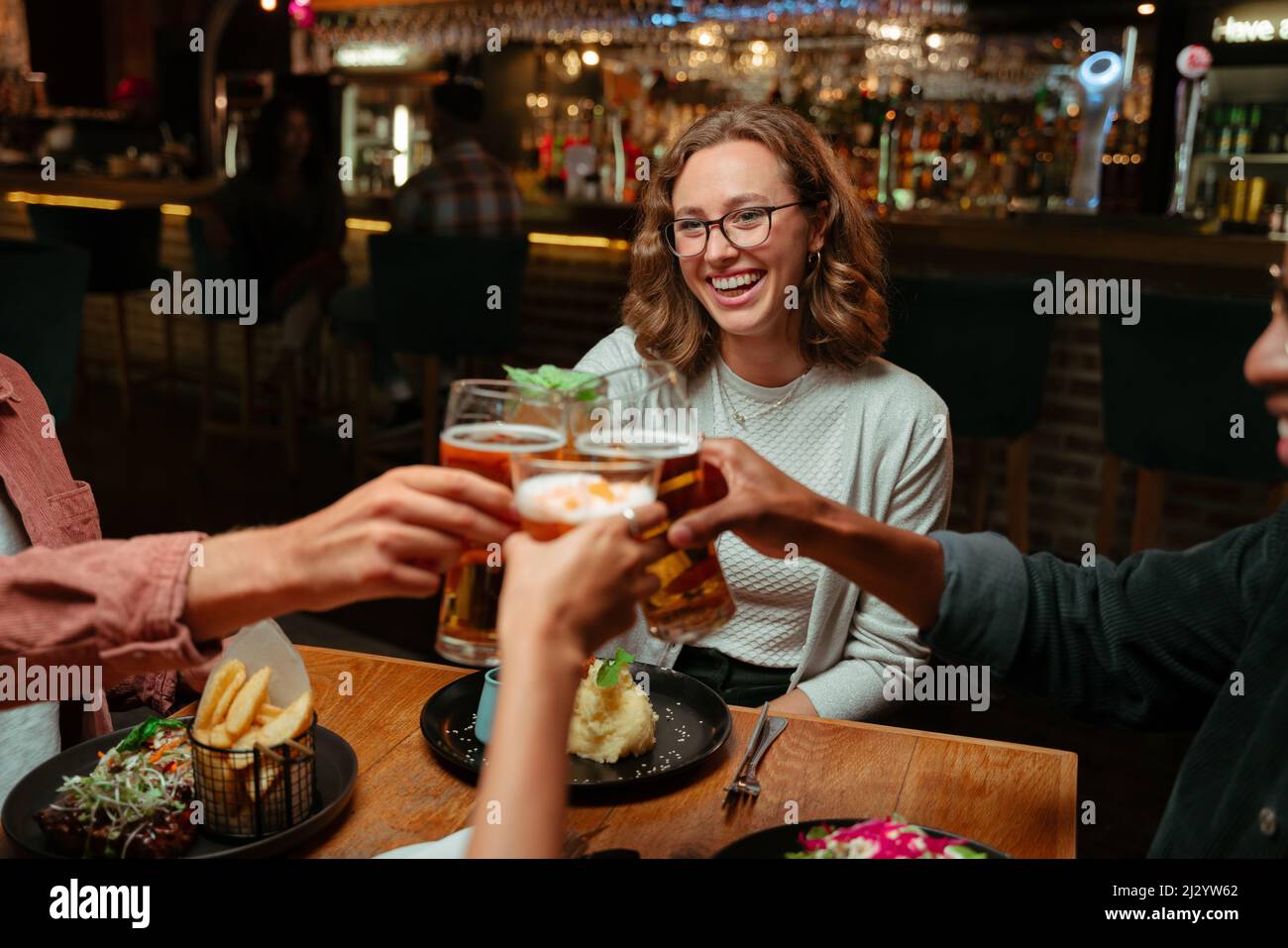 Diverse group of friends out for dinner drinking cocktails making a ...