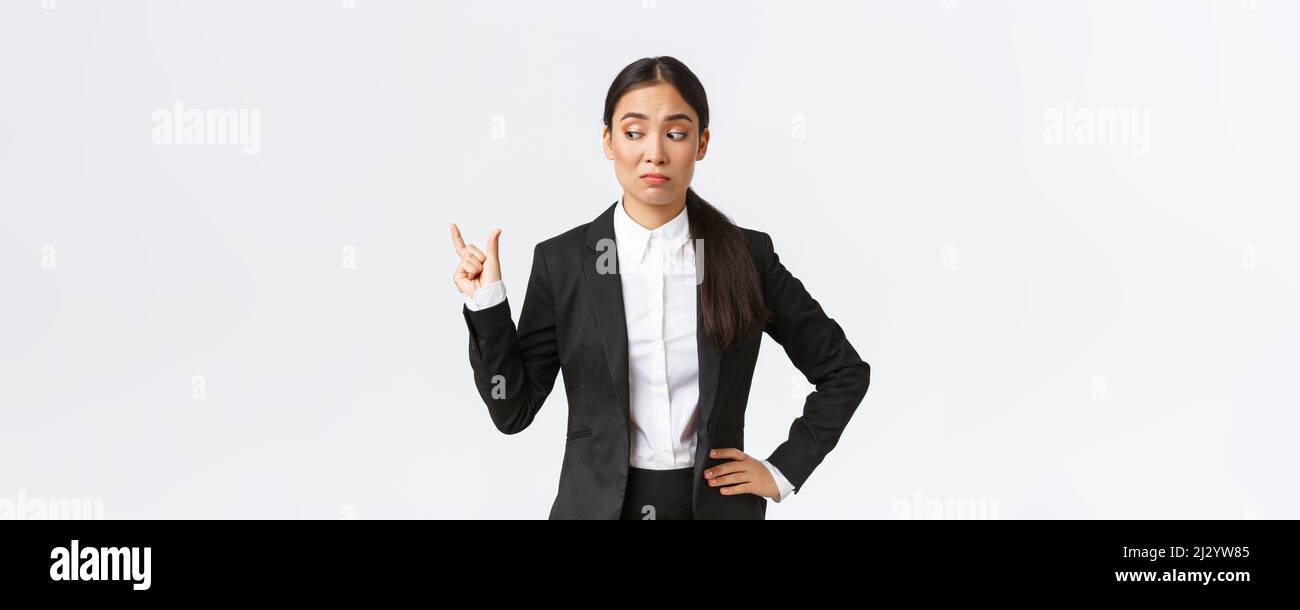 Skeptical and awkward young asian businesswoman, saleswoman in black ...