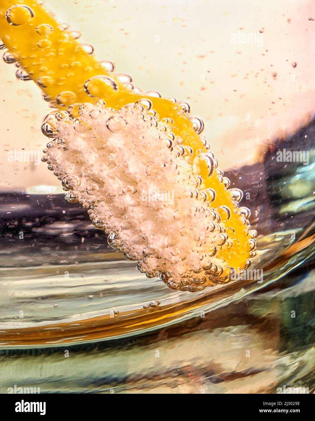 Macro still life of yellow toothbrush in glass showing bubbles formed ...