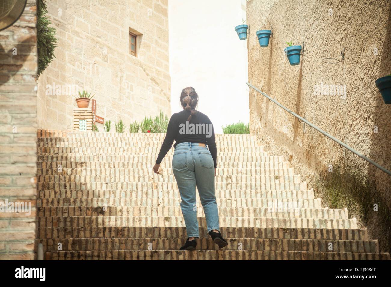 A back view of a woman looking around while walking up stairs of old ...