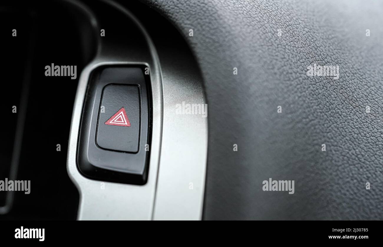 Red warning light triangle button in modern car interior panel, closeup ...