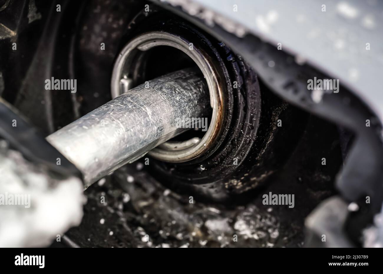 Metal fuel nozzle, filling gas tank of car covered with snow in winter ...