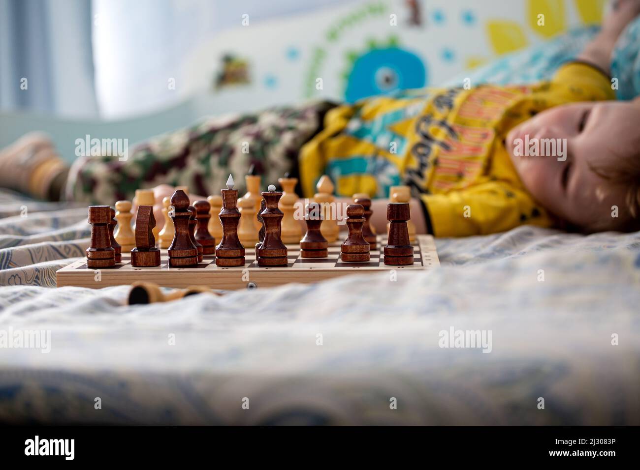 A chess board with chess pieces on the background of a tired child ...