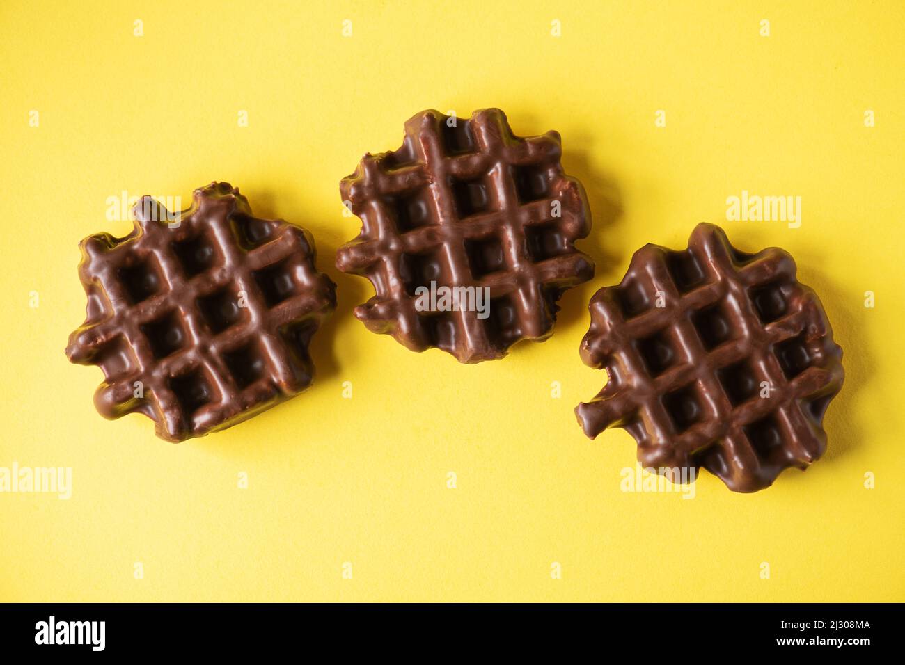 Three chocolate waffles on a yellow background, flat lay, top view ...
