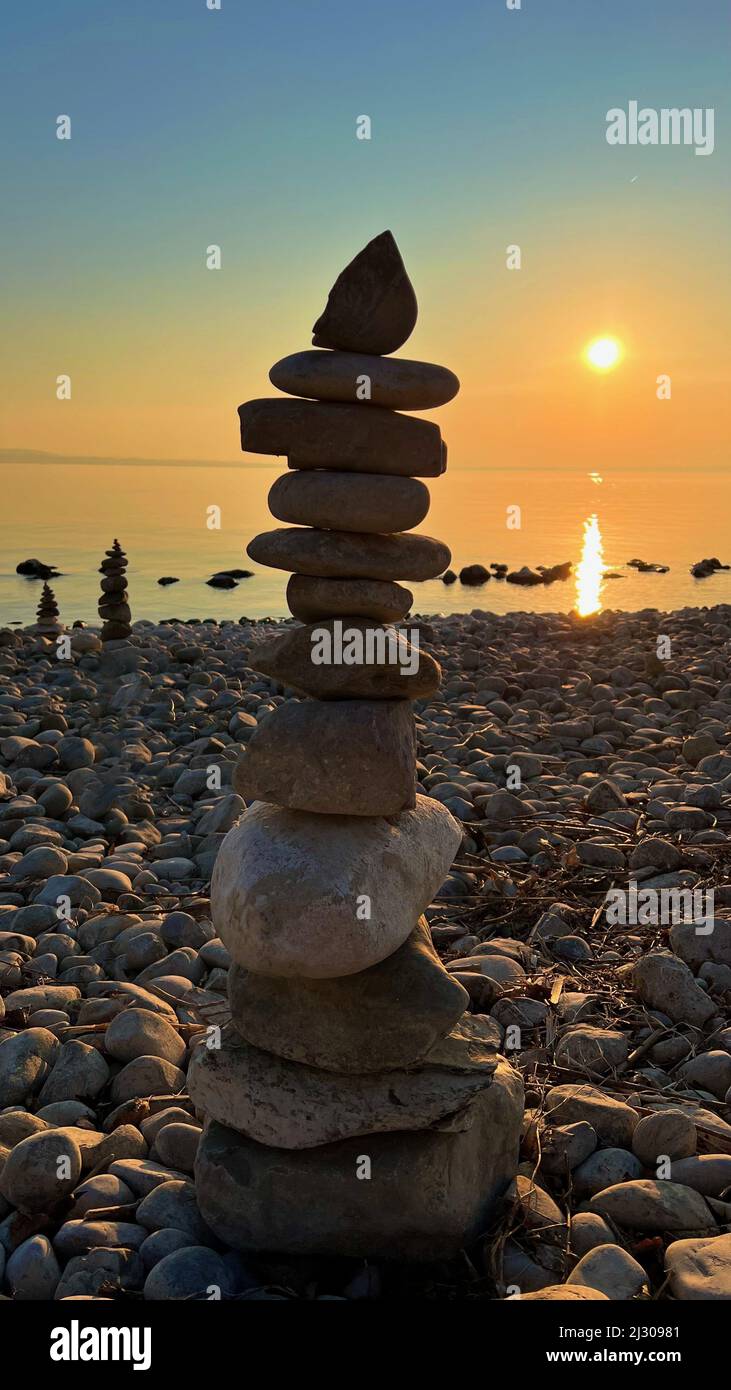 A vertical of stack of pebbles on the beach during the sunset Stock ...