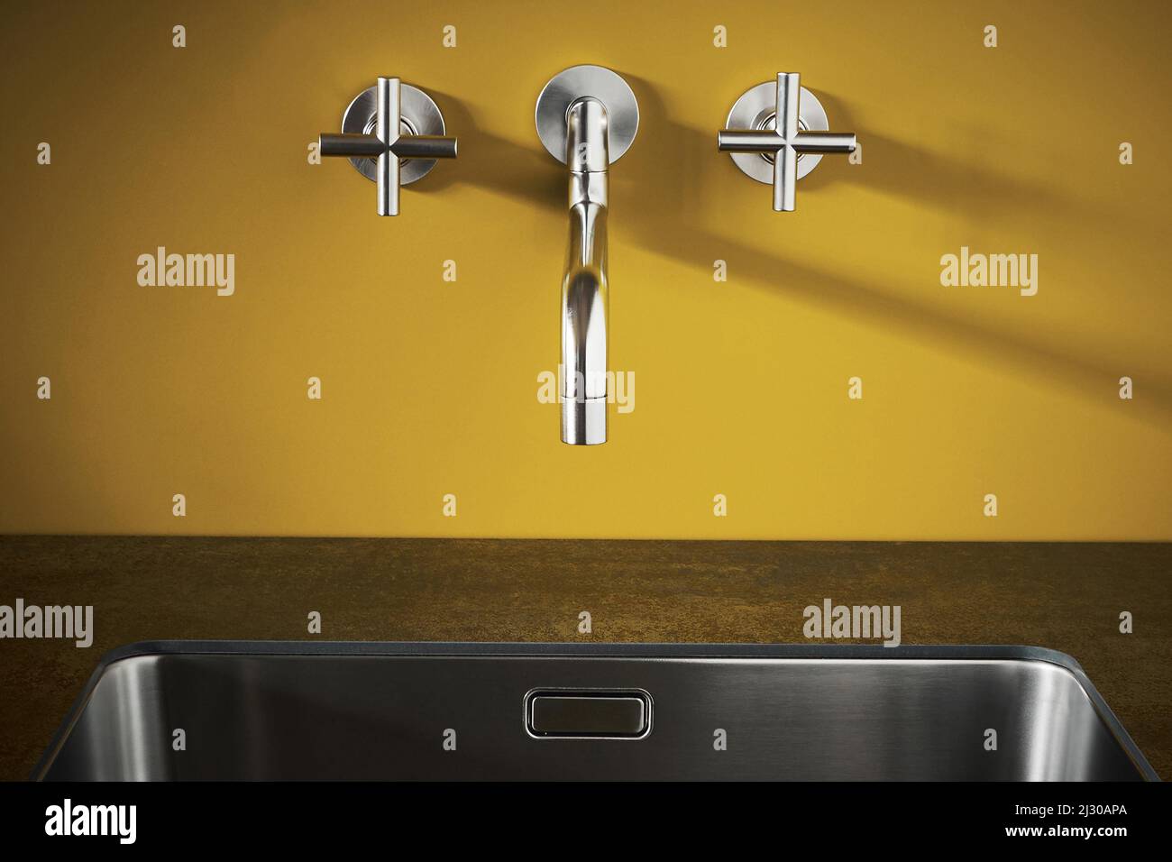 Close up photo of faucet and sink in the kitchen. Yellow background ...