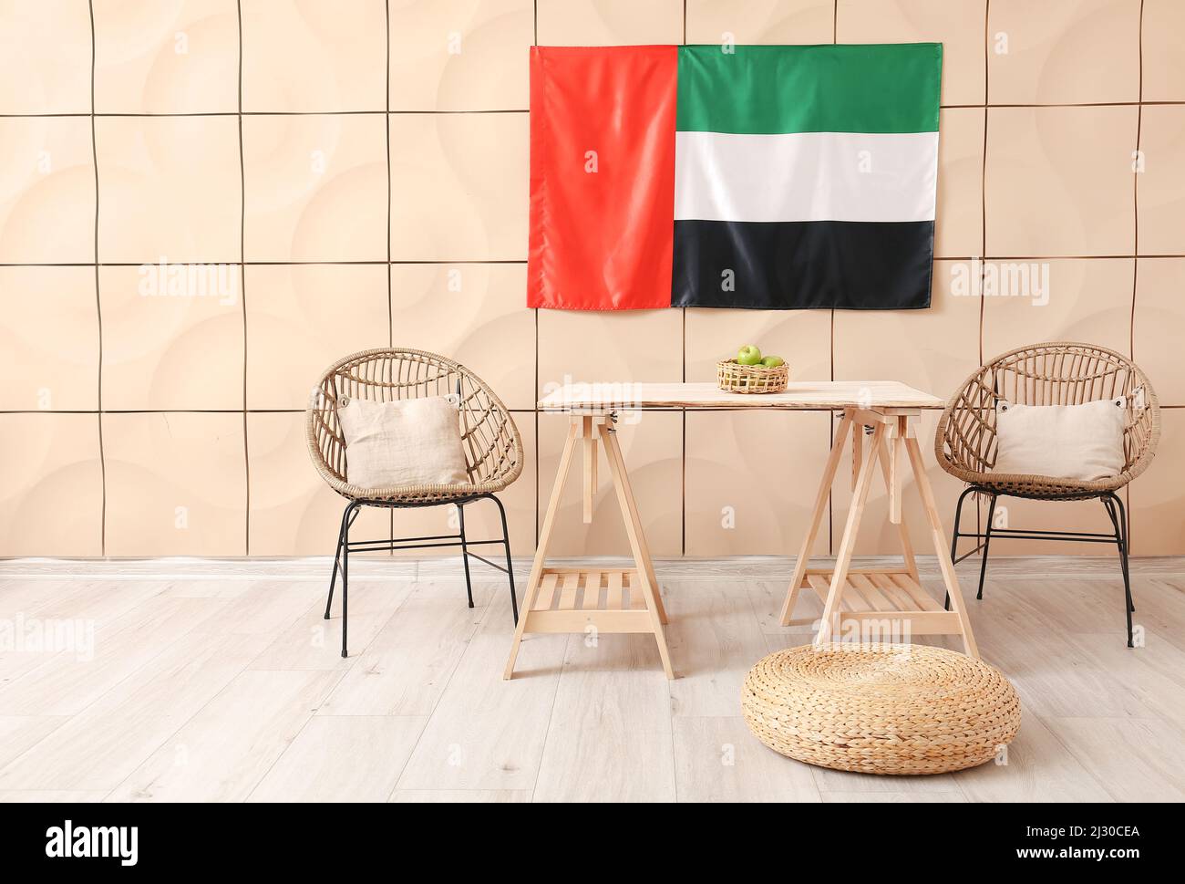 Dining table with apples, chairs and UAE flag hanging on beige wall ...