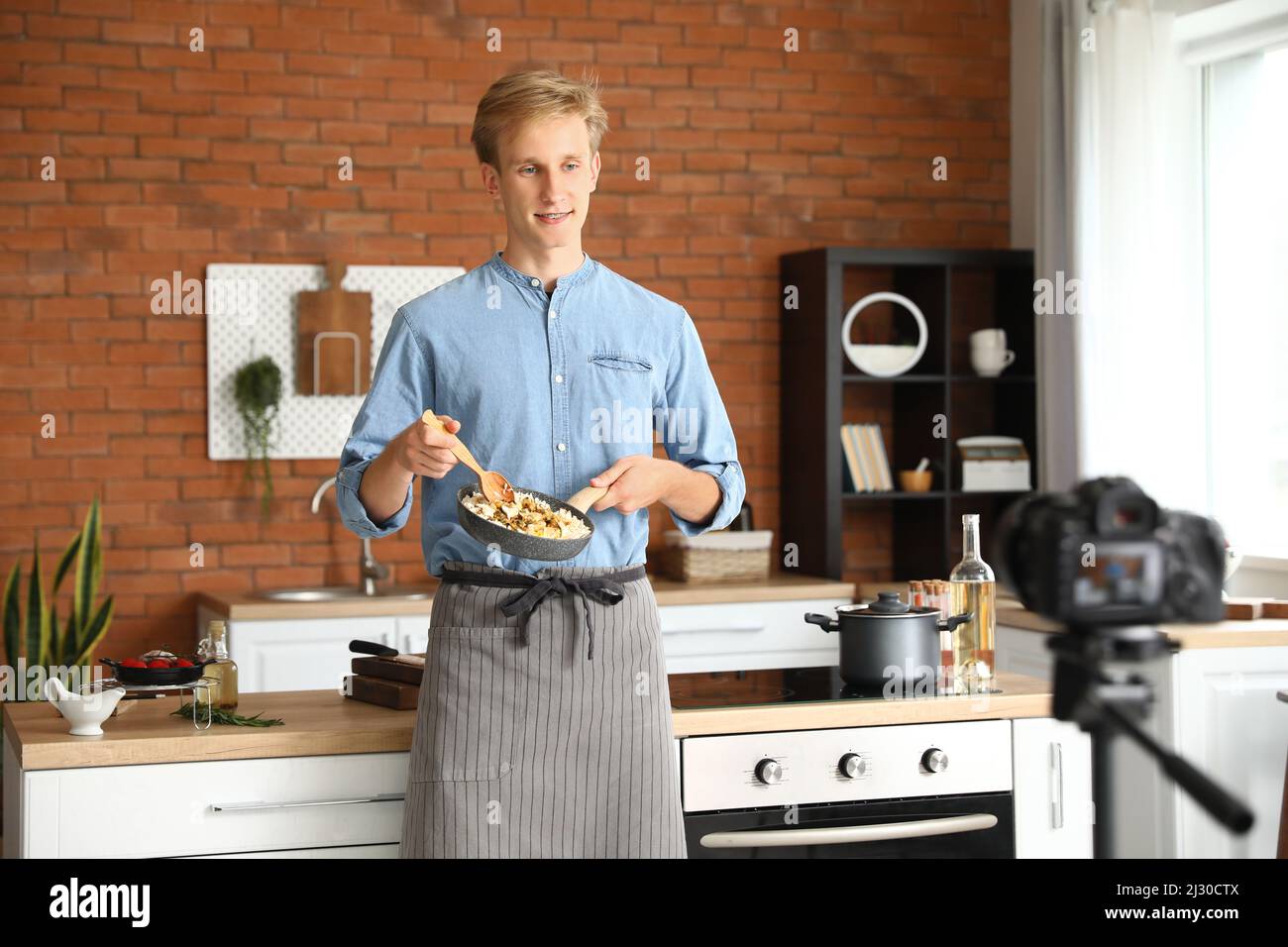 Young man cooking tasty rice while recording video tutorial in kitchen ...