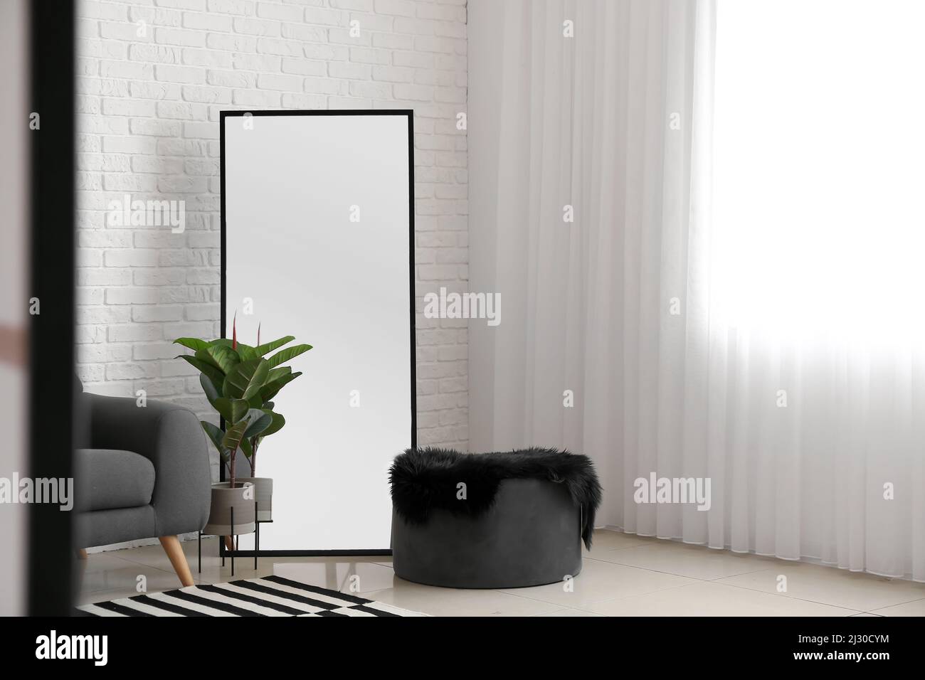 Mirror, sofa and pouf in stylish living room interior Stock Photo - Alamy