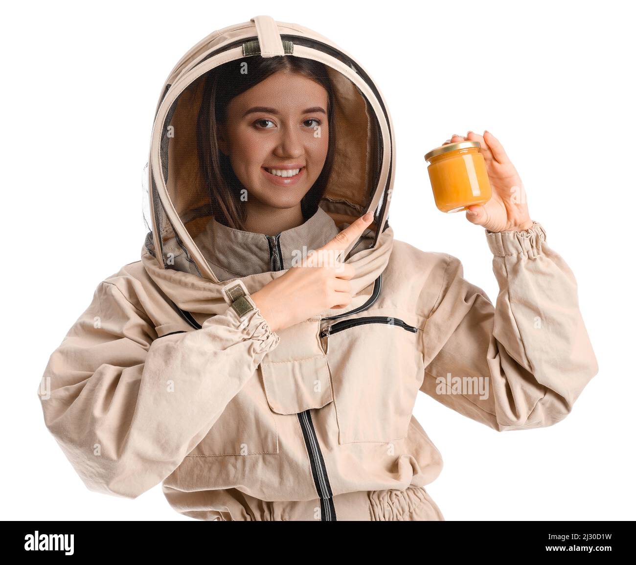 Female beekeeper in protective suit pointing at jar of honey on white ...