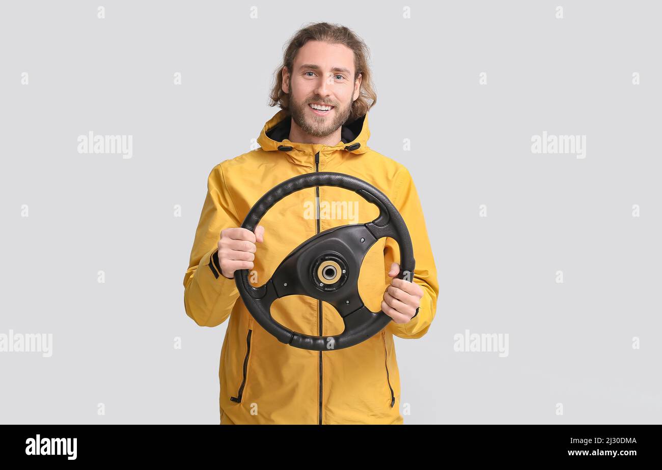 Handsome man with steering wheel on grey background Stock Photo - Alamy