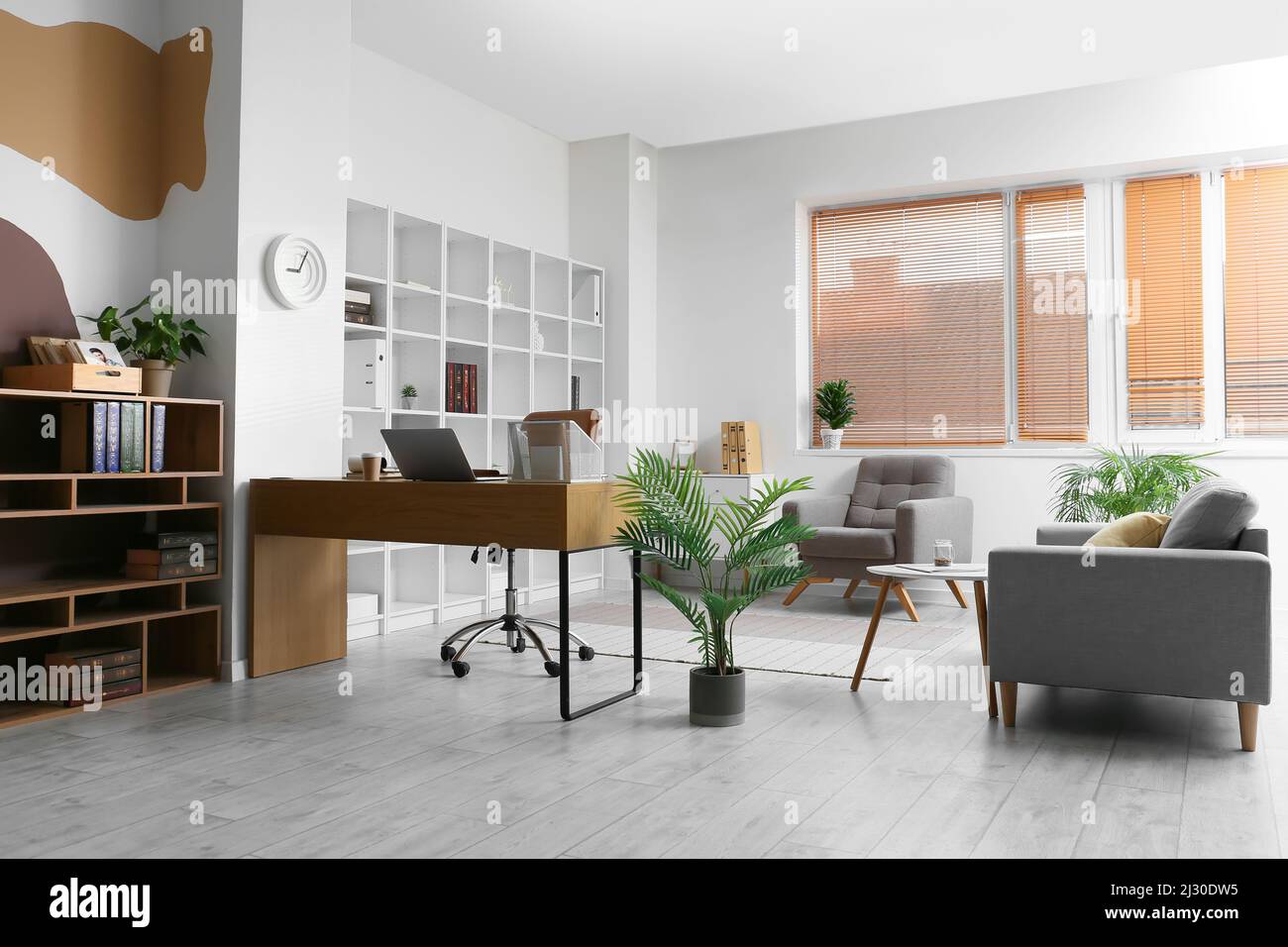 Interior of office with modern furniture and stylish clock on light ...