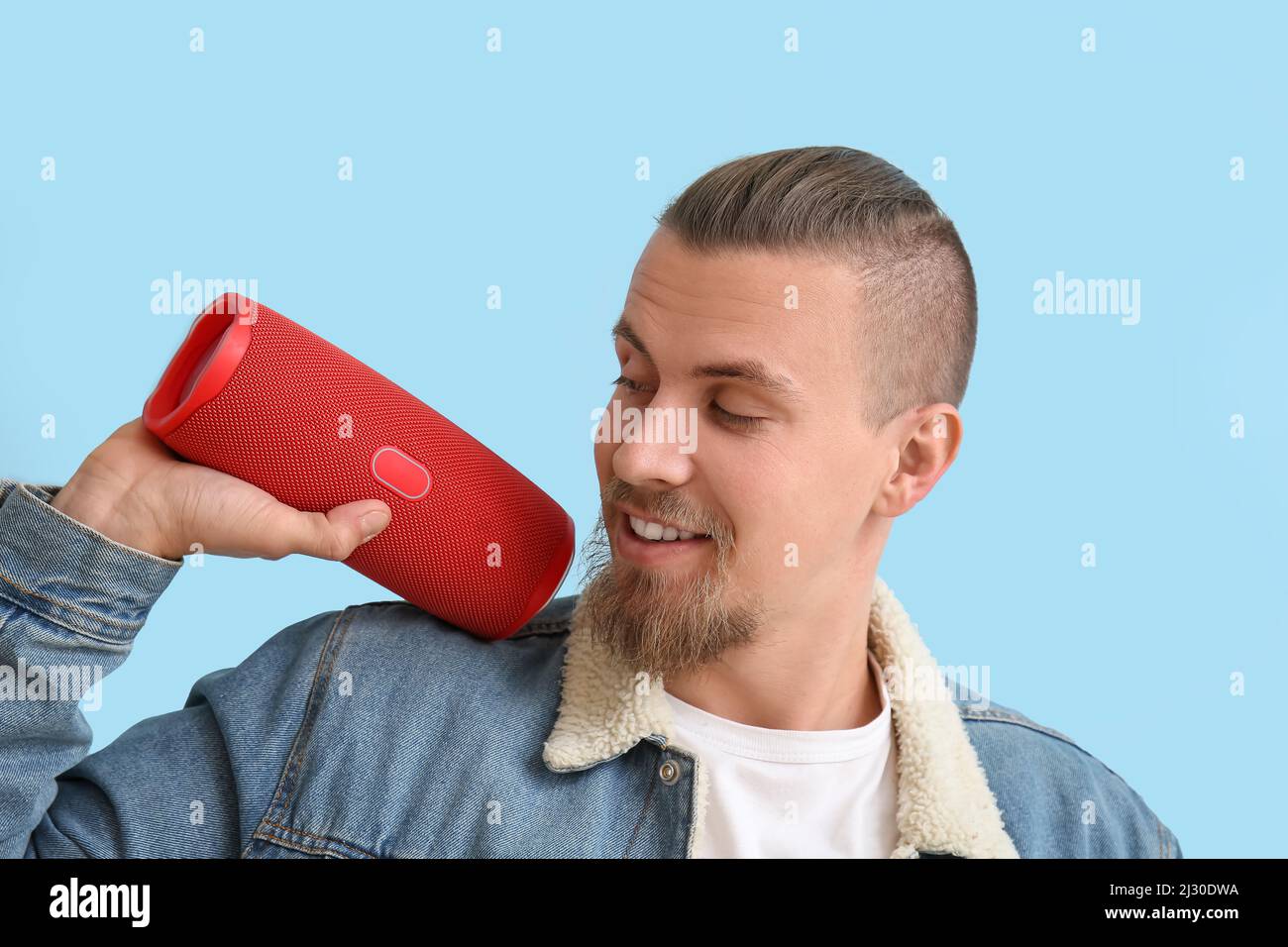 Man holding wireless portable speaker on shoulder against blue ...