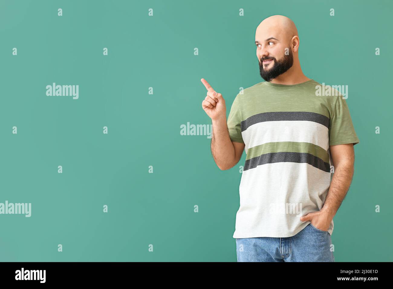 Portrait of handsome bald man pointing at something on green background ...