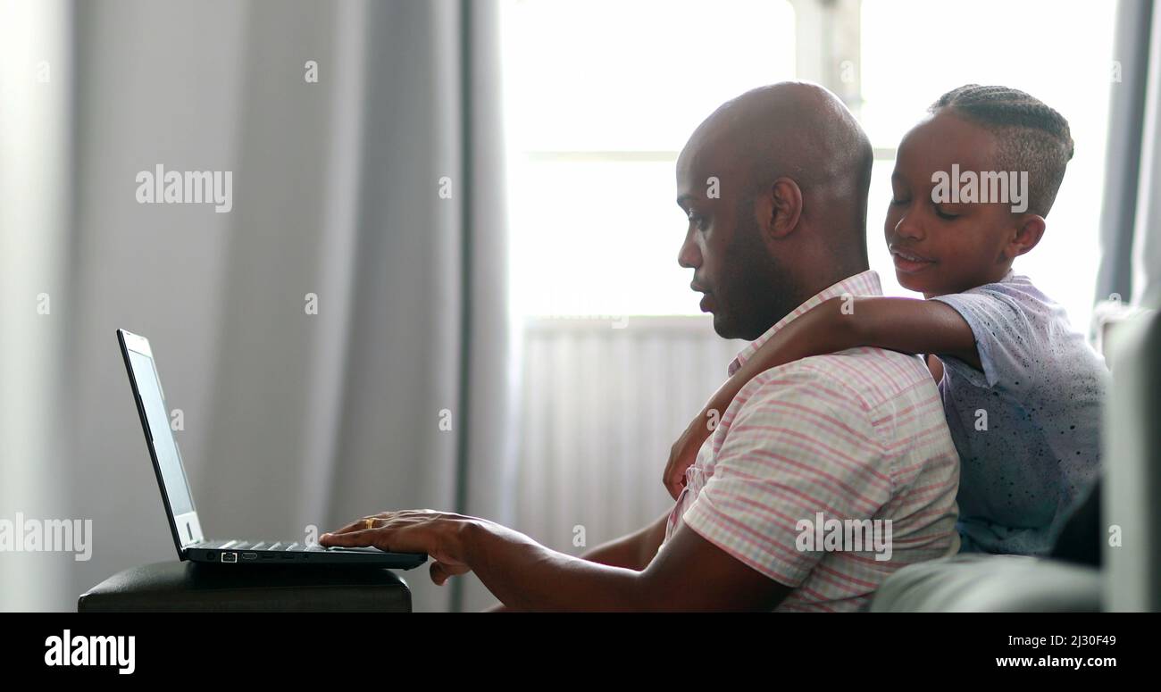 African parent using laptop computer with child son Stock Photo - Alamy