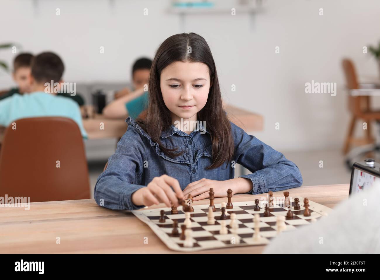 Little girl playing chess during tournament in club Stock Photo - Alamy