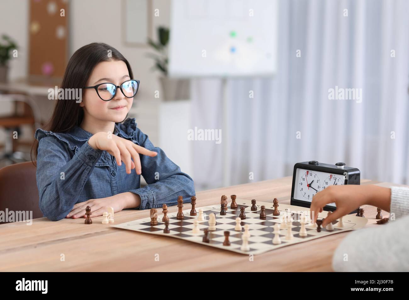 Little girl playing chess during tournament in club Stock Photo - Alamy