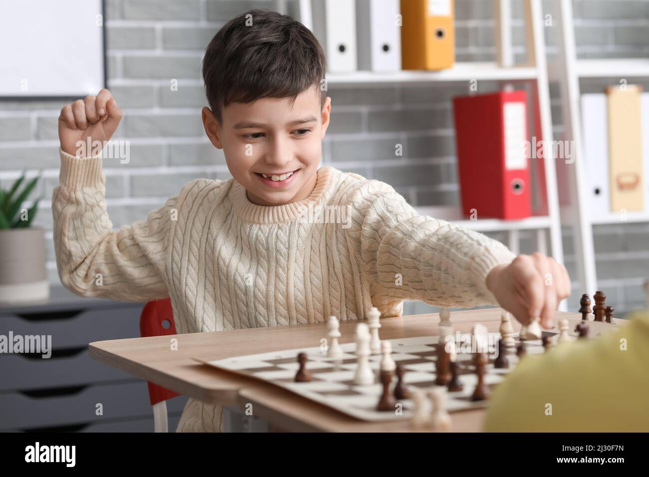 Happy little boy playing chess during tournament in club Stock Photo ...