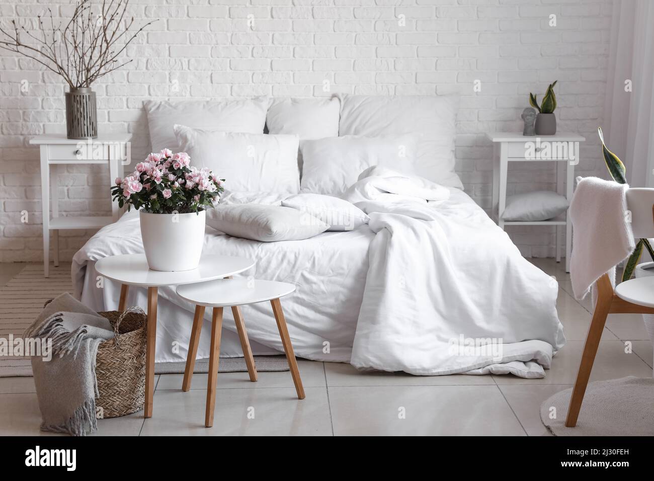 Beautiful begonia flowers and comfortable bed near white brick wall in ...