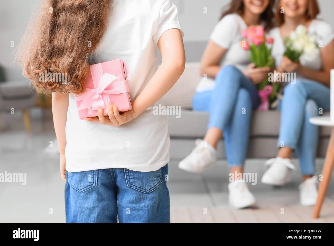 Little girl greeting her family for International Women's Day at home ...