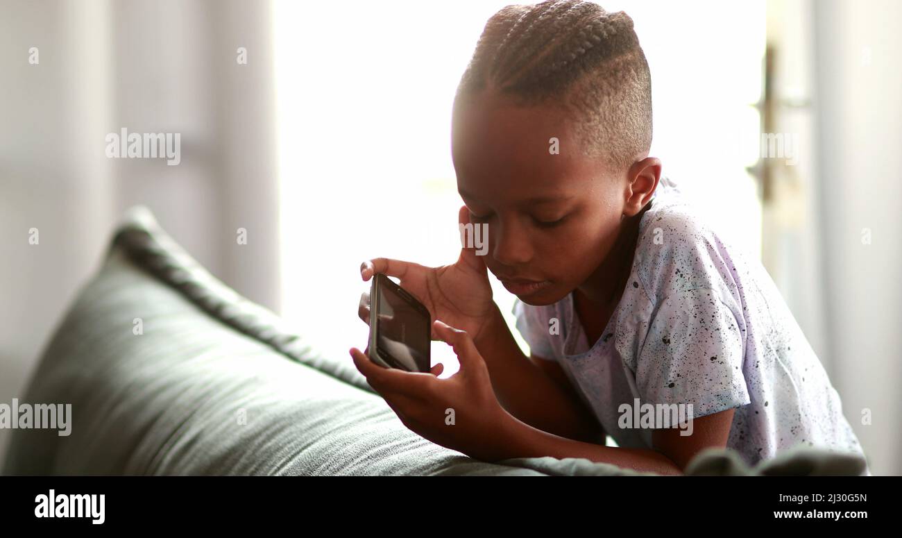 Kid scratching face while using phone playing game Stock Photo - Alamy