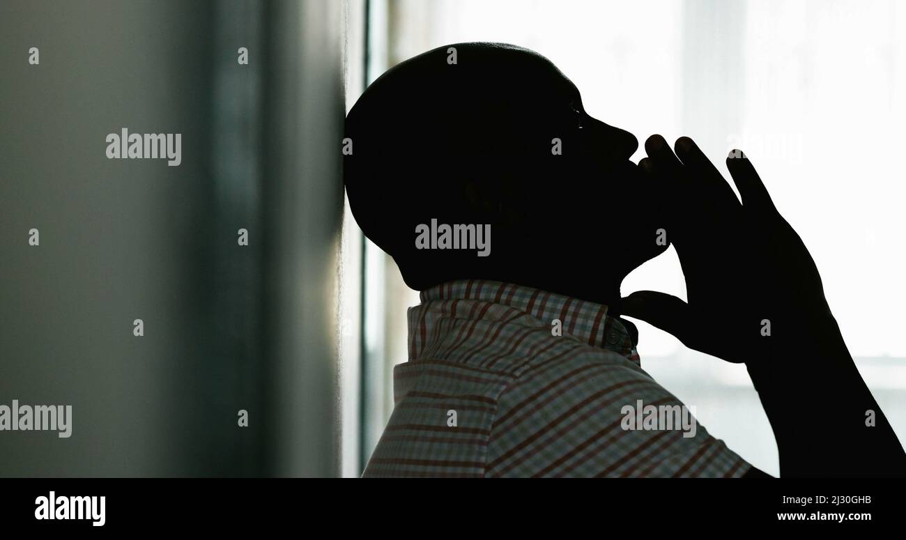 Troubled black man leaning on wall in anguish, silhouette of African ...