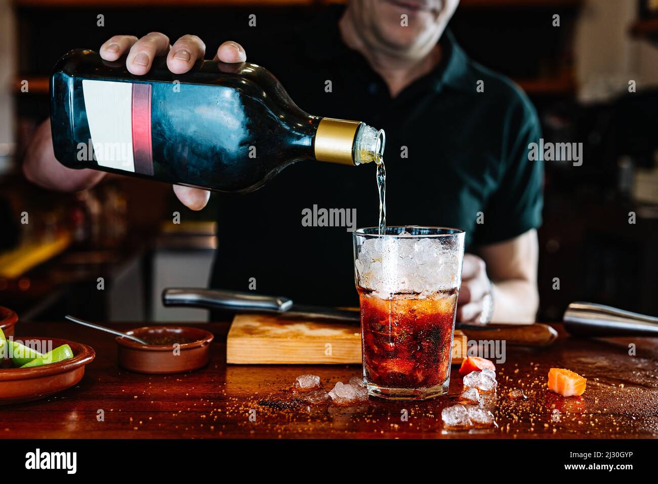 Detail of the hands of an experienced waiter pouring liquor into a ...