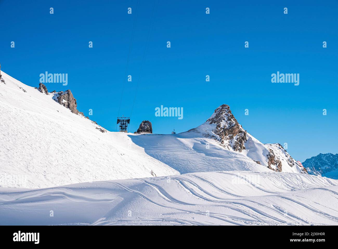 View of ski tracks on snowy mountain against clear blue sky Stock Photo ...